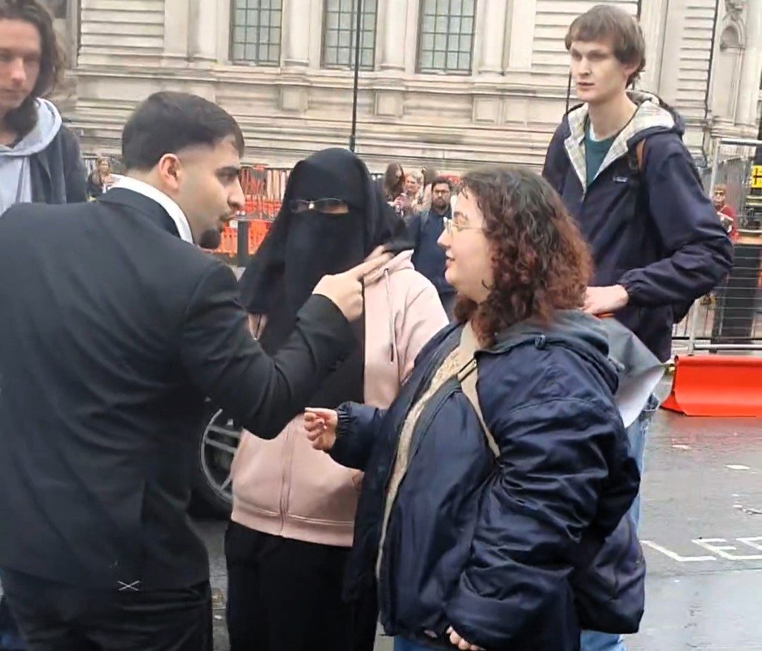 Suited man in ‘ankle tag’ pushes protesters who are blocking his way to ...